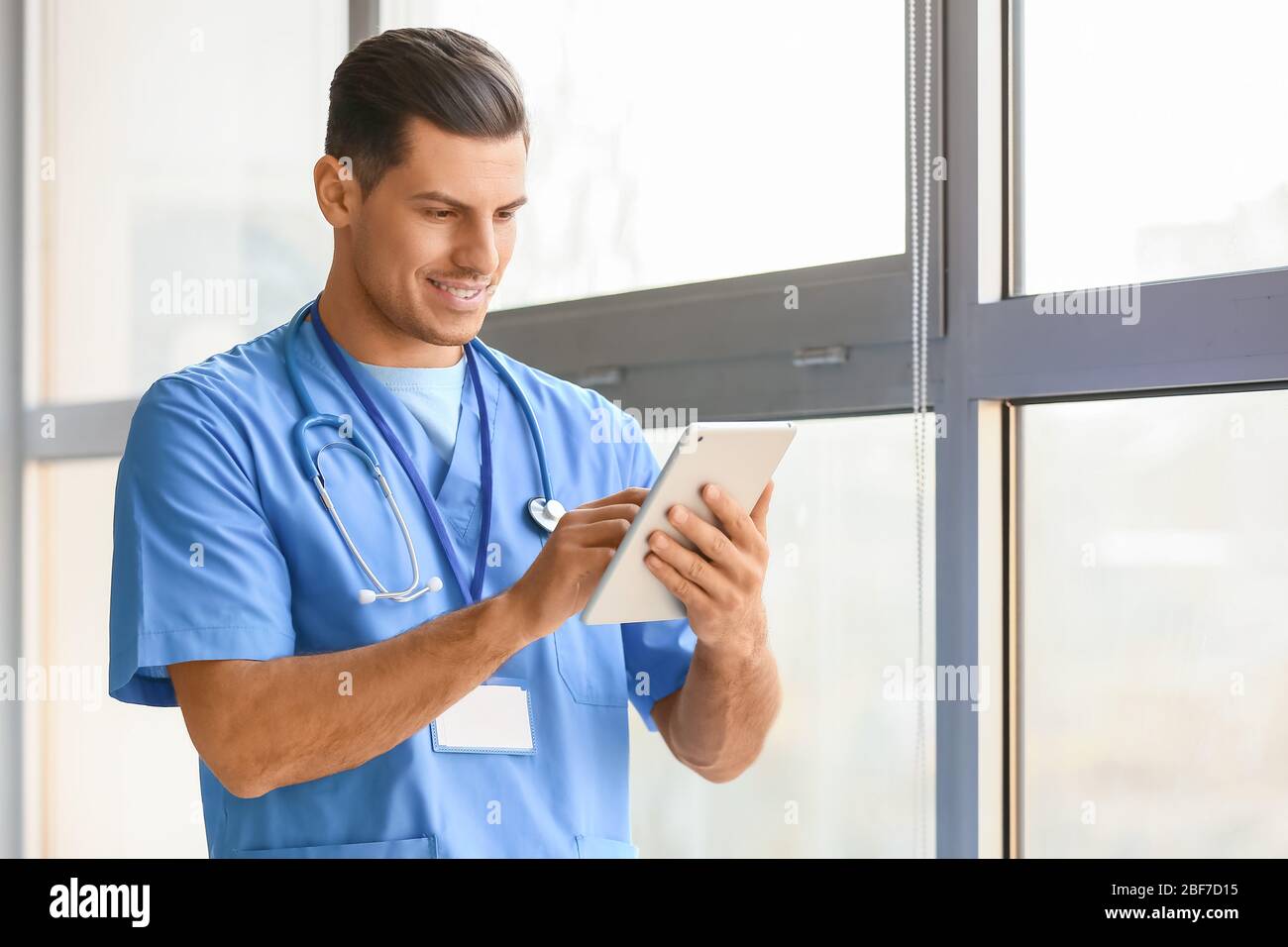 Portrait of young male doctor with tablet computer near window Stock ...