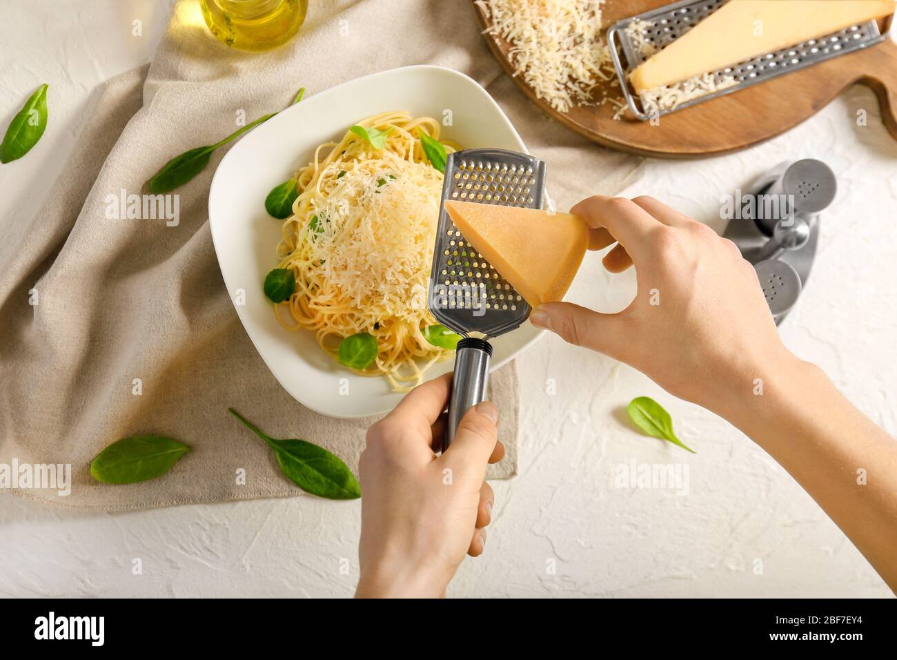 Woman grating cheese onto plate with tasty pasta, top view Stock Photo ...
