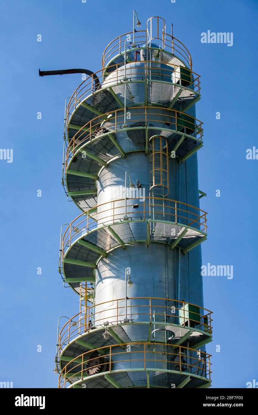 Close-up of grey metal distillation tower. Oil refining column on blue ...