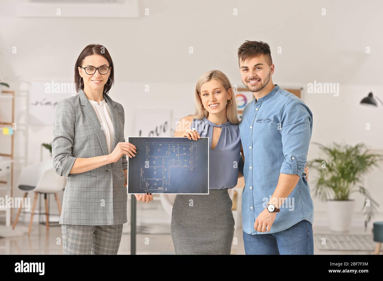Female interior designer with couple and house plan in office Stock ...