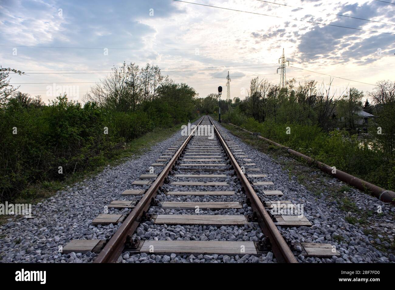 Country railroad going forward in the distance, under dramatic sunset ...