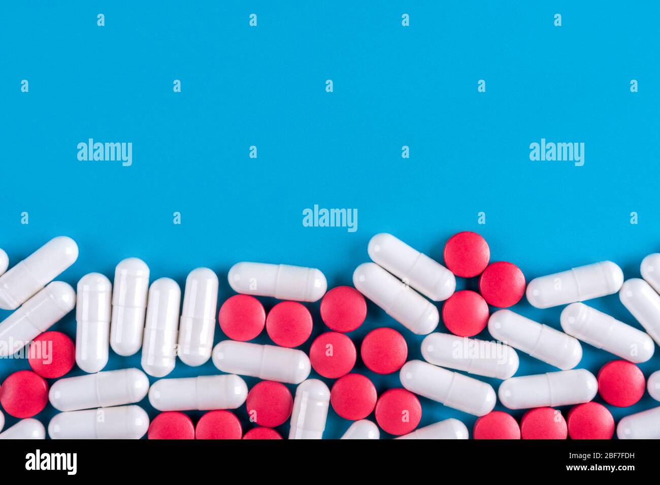 Blue background with red and white tablets. Background for a medical ...