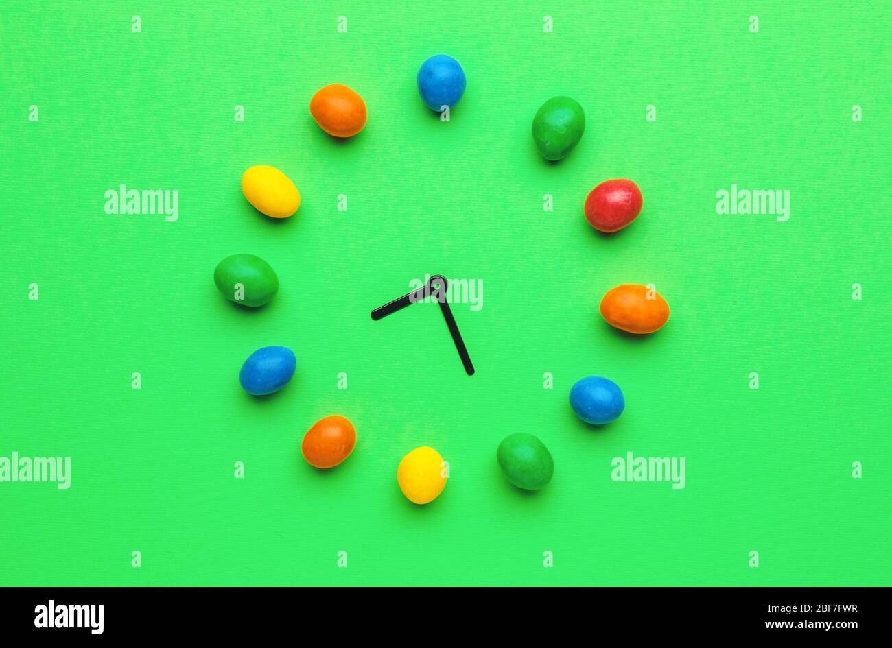 Creative clock made of candies on color background Stock Photo - Alamy
