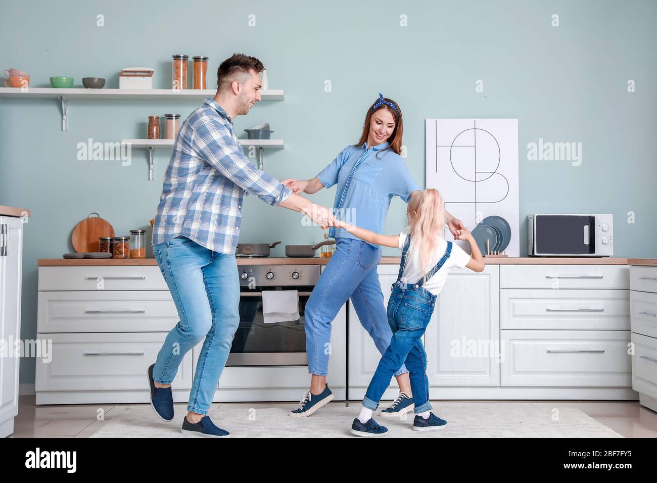 Happy family dancing in kitchen Stock Photo - Alamy