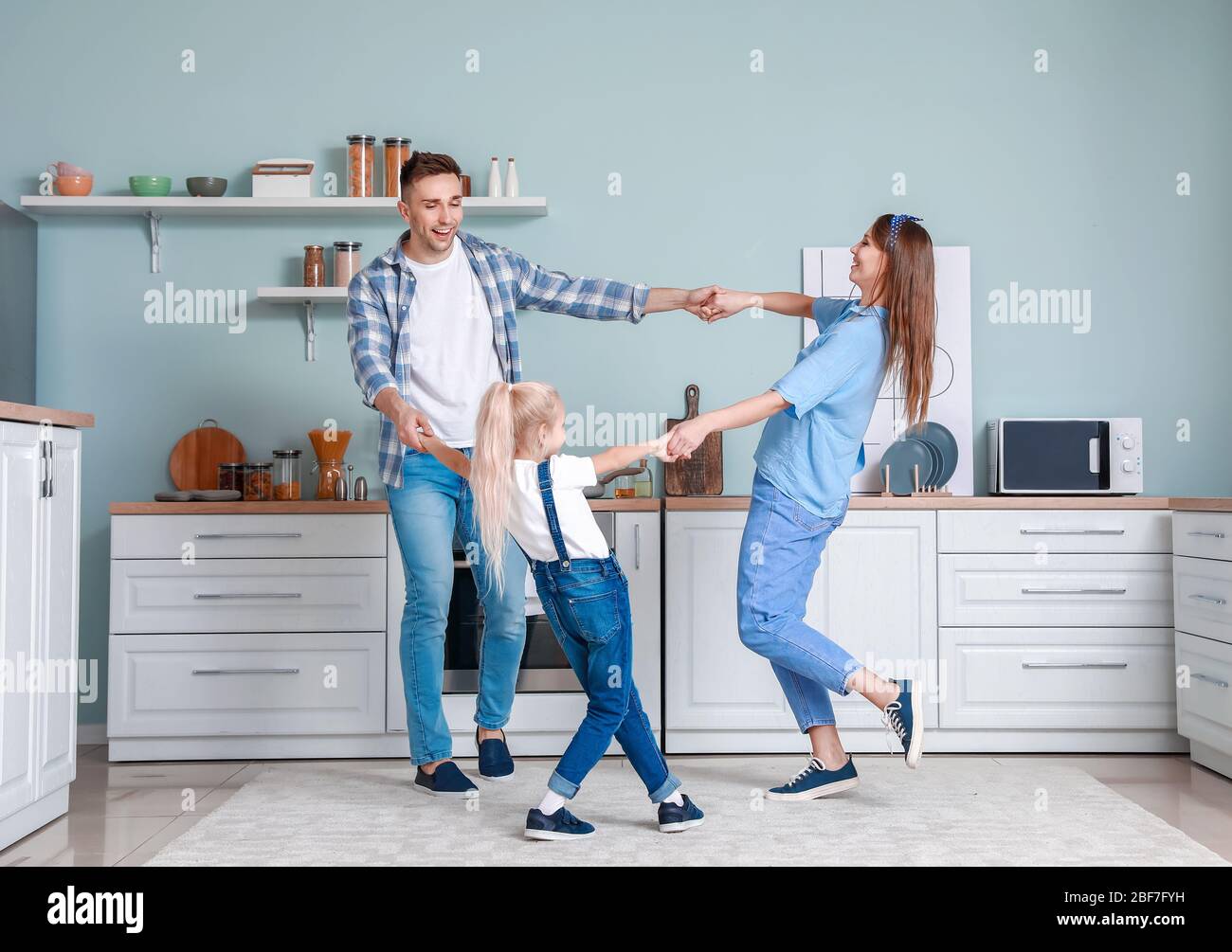 Happy family dancing in kitchen Stock Photo - Alamy
