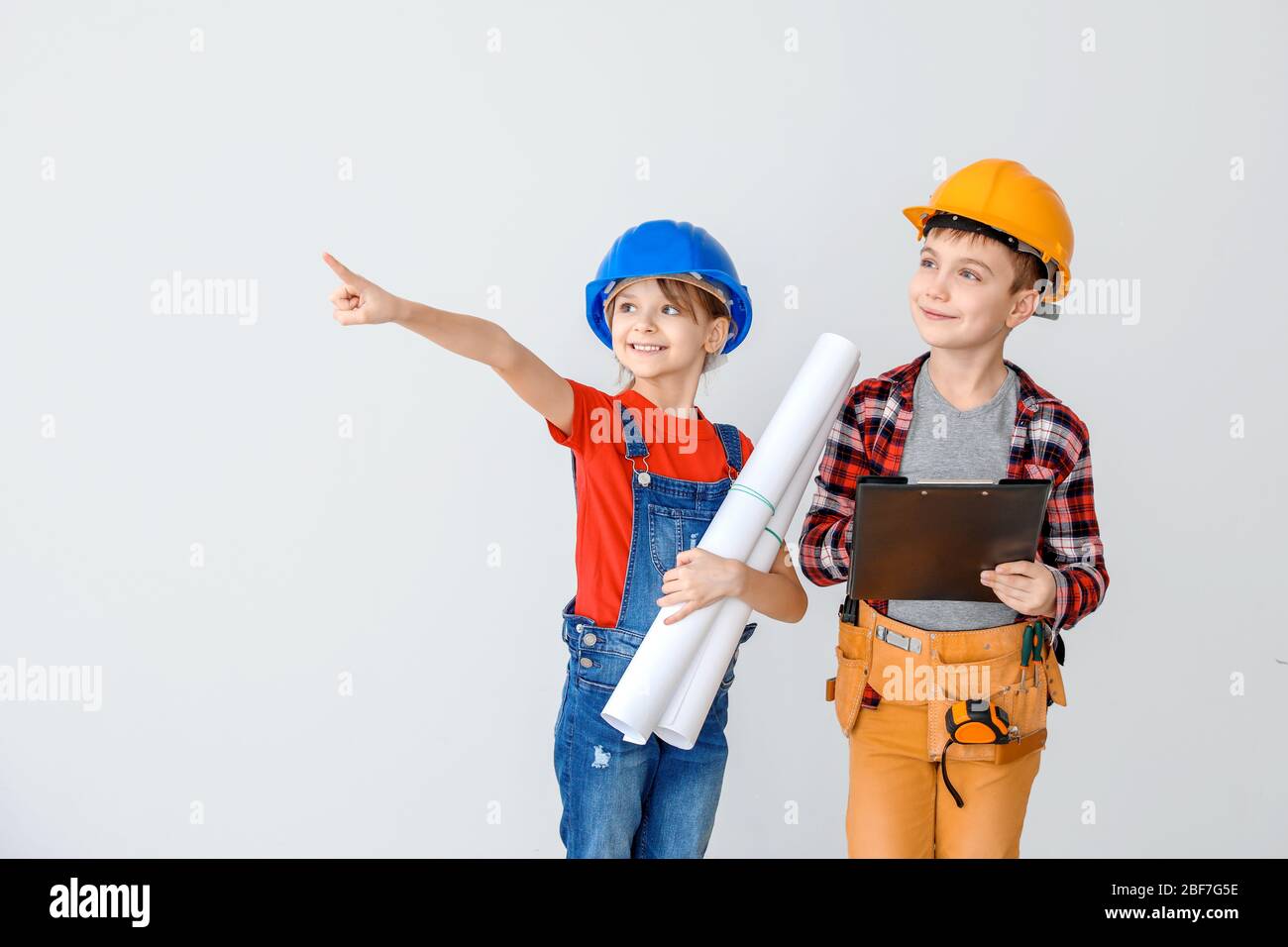 Cute little architects on light background Stock Photo - Alamy