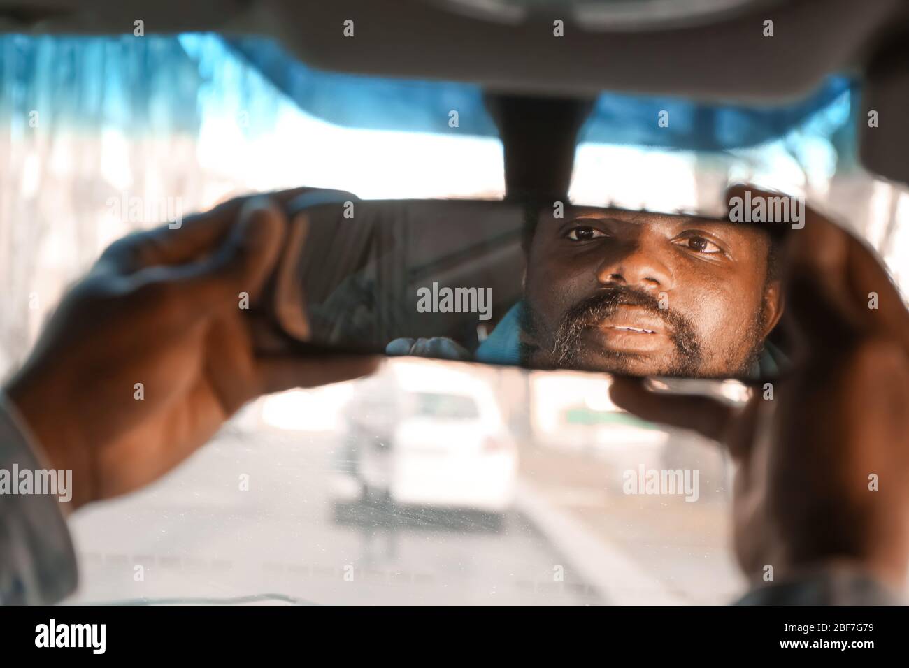 Driver adjusting rear view mirror in car Stock Photo - Alamy