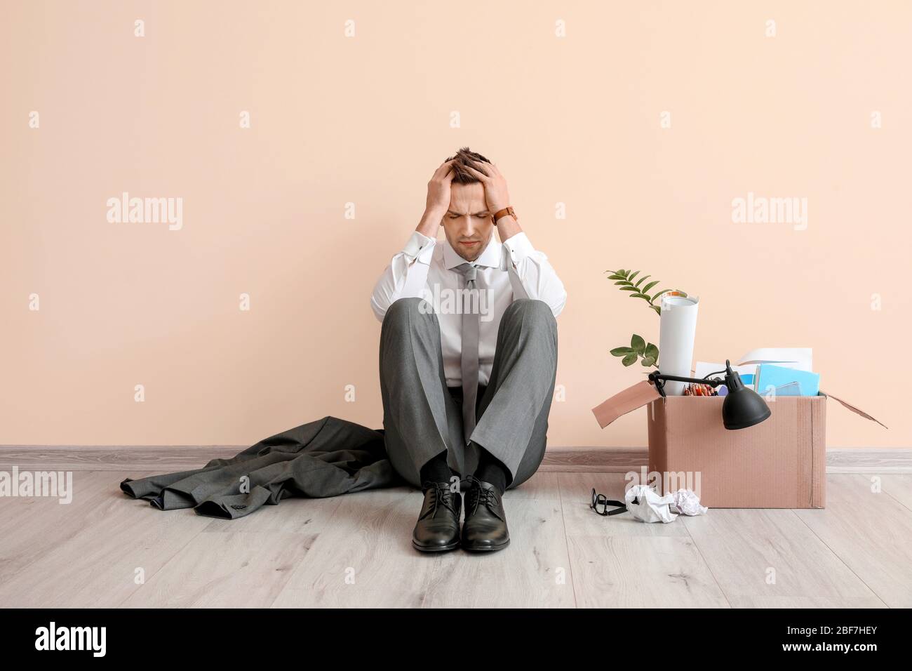 Sad fired man sitting near color wall Stock Photo - Alamy