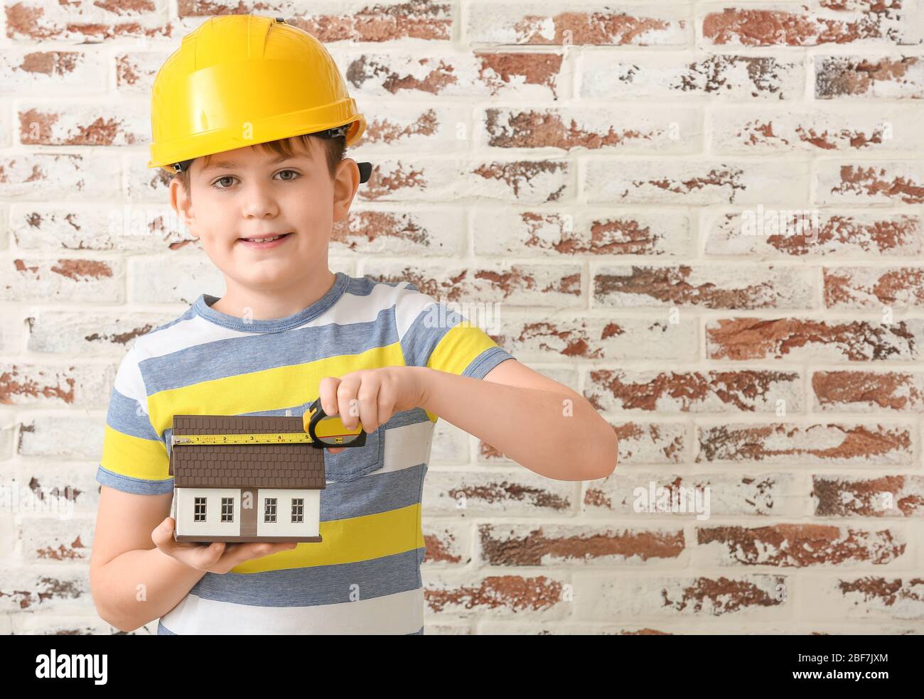 Cute little builder on brick background Stock Photo - Alamy