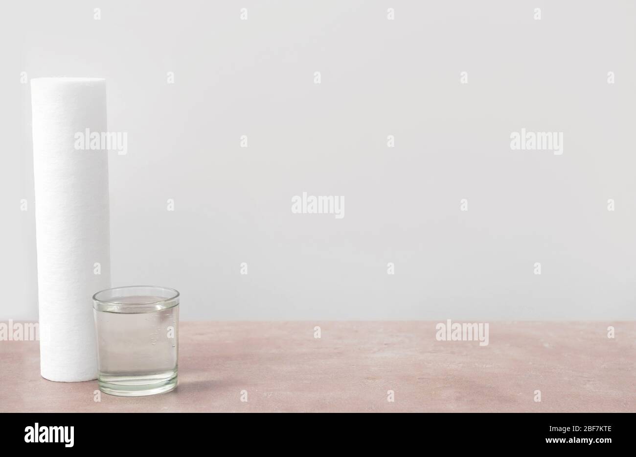 Glass of clean water and filter on table Stock Photo - Alamy