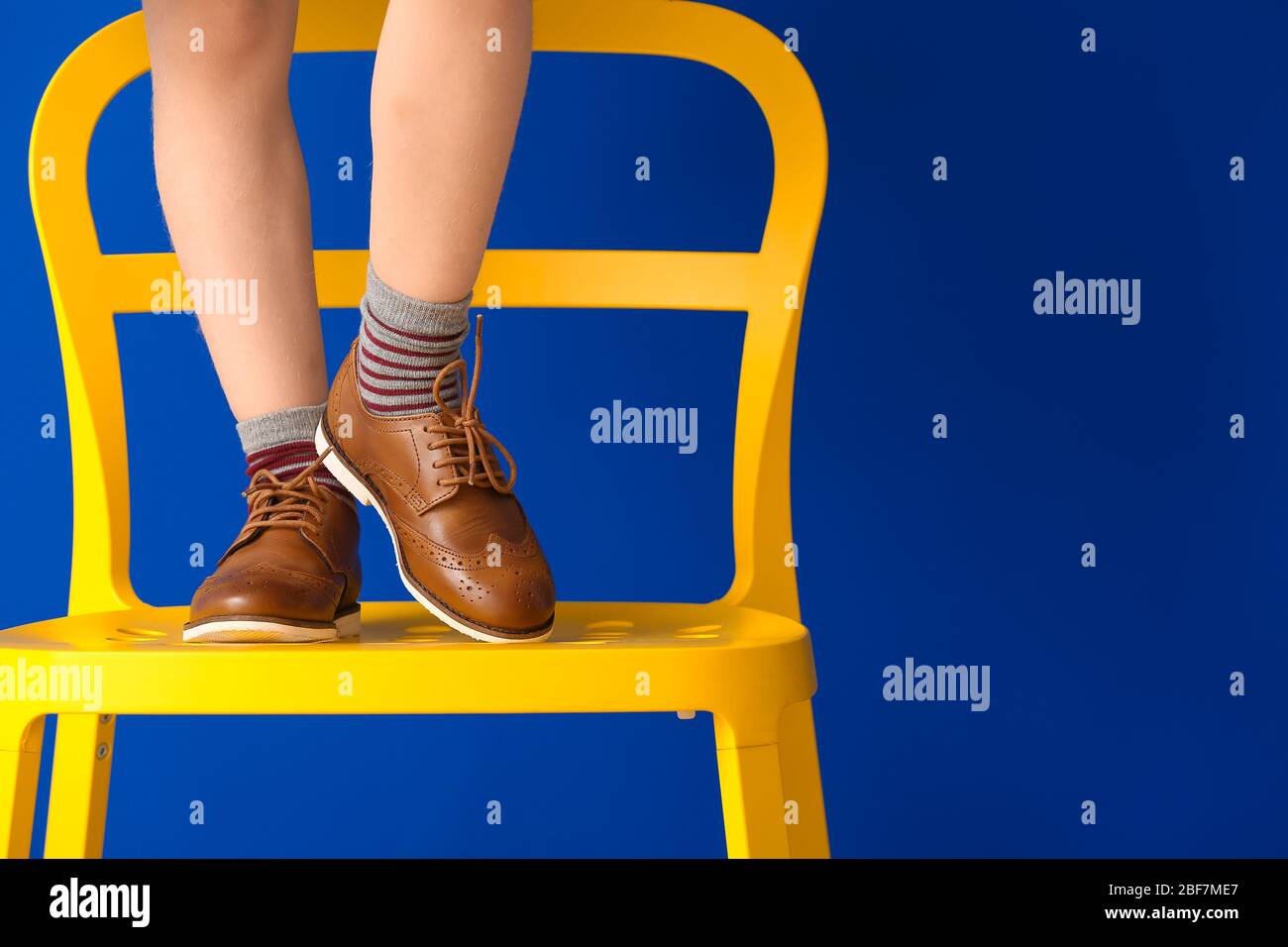 Little girl standing on chair against color background Stock Photo - Alamy