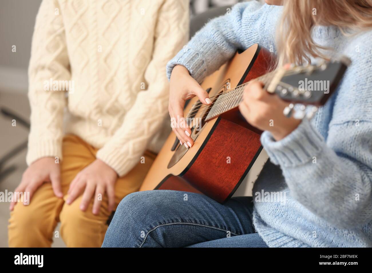 Private music teacher giving guitar lessons to little boy at home ...