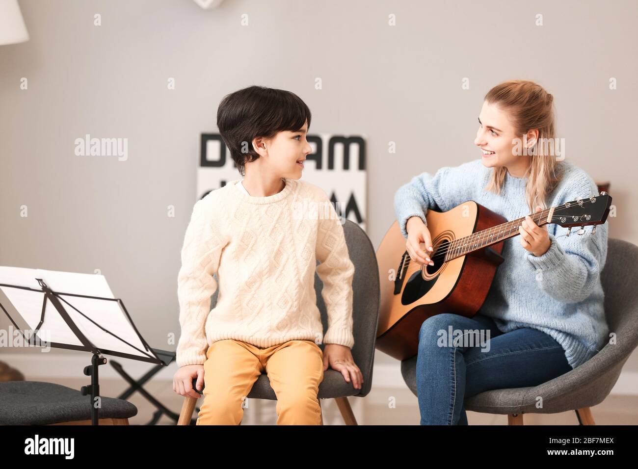 Private music teacher giving guitar lessons to little boy at home Stock ...