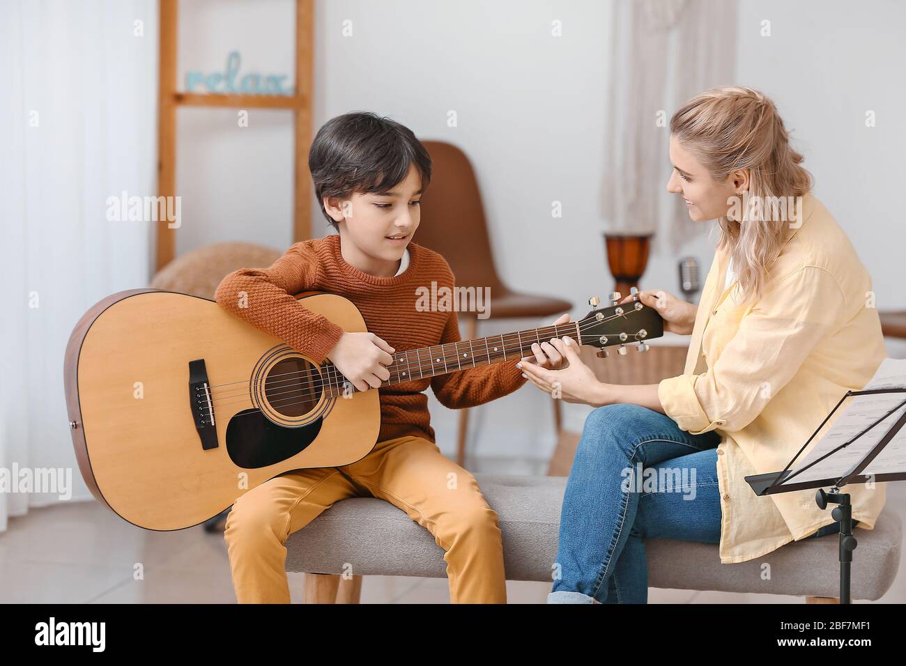 Private music teacher giving guitar lessons to little boy at home Stock ...