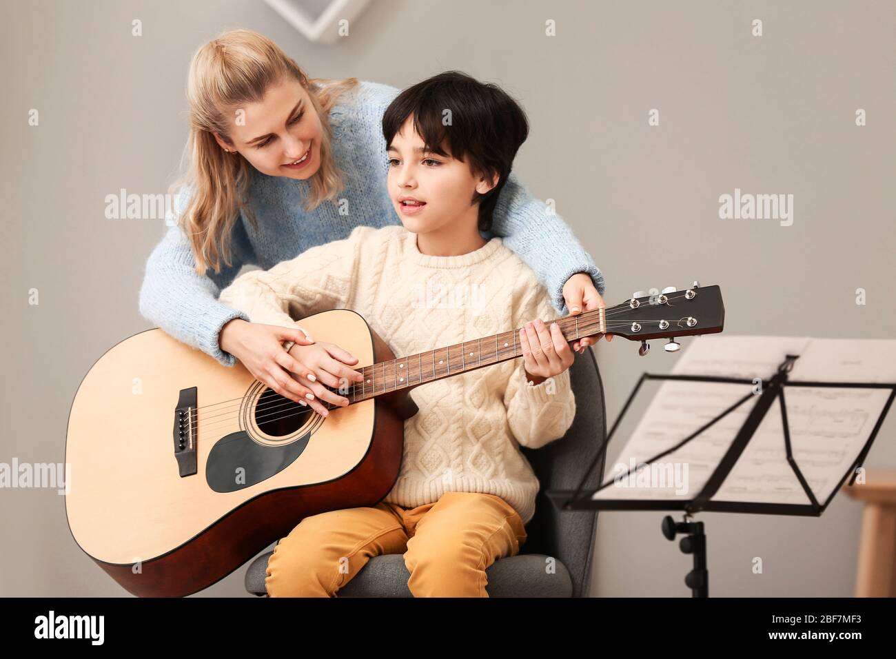 Private music teacher giving guitar lessons to little boy at home Stock ...