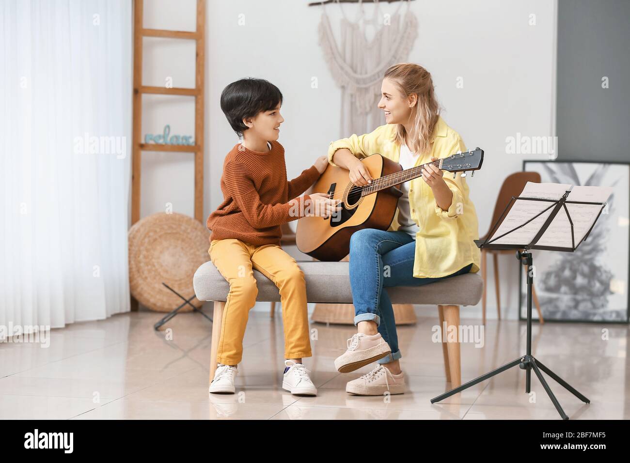 Private music teacher giving guitar lessons to little boy at home Stock ...