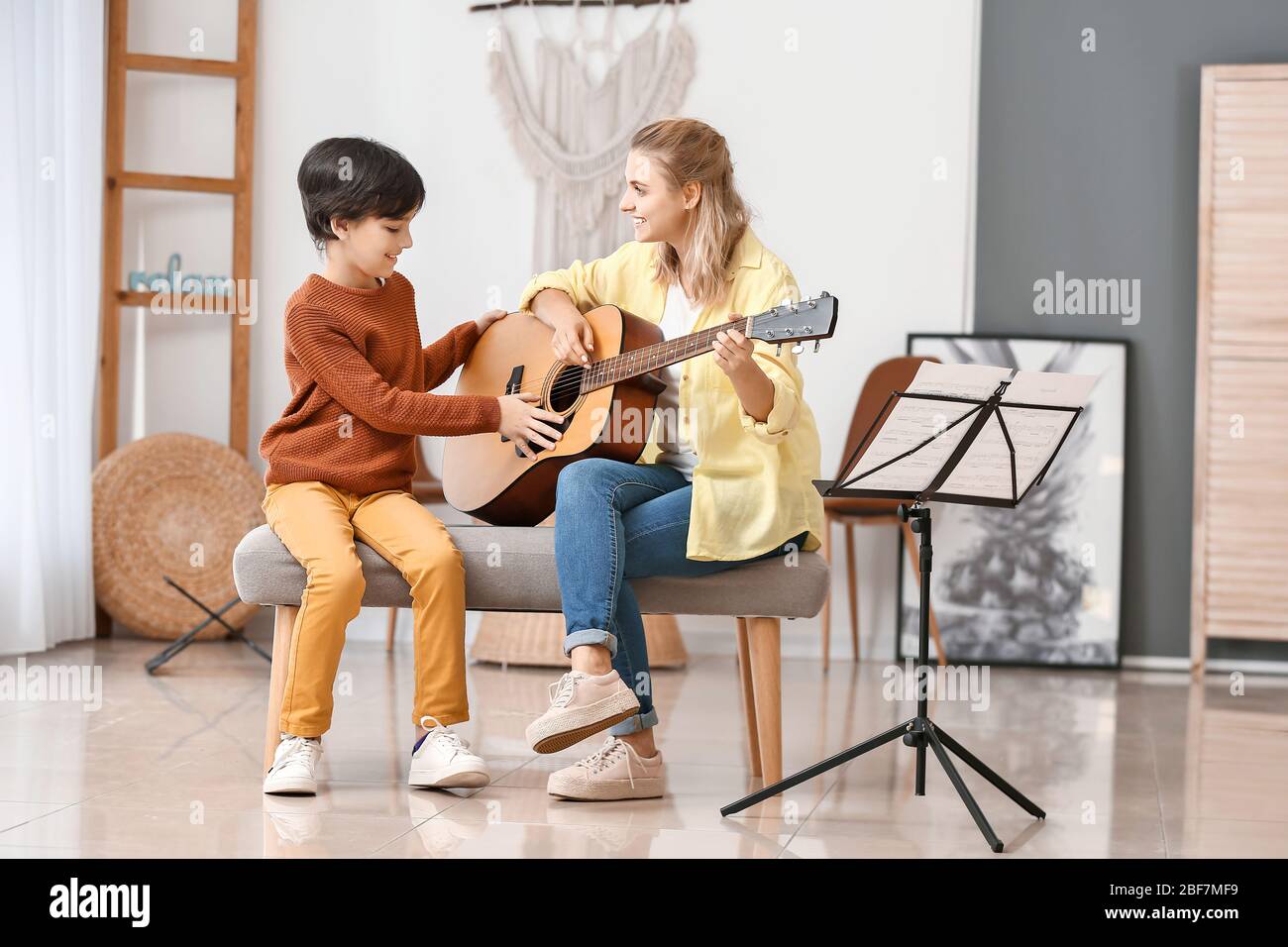 Private music teacher giving guitar lessons to little boy at home Stock ...