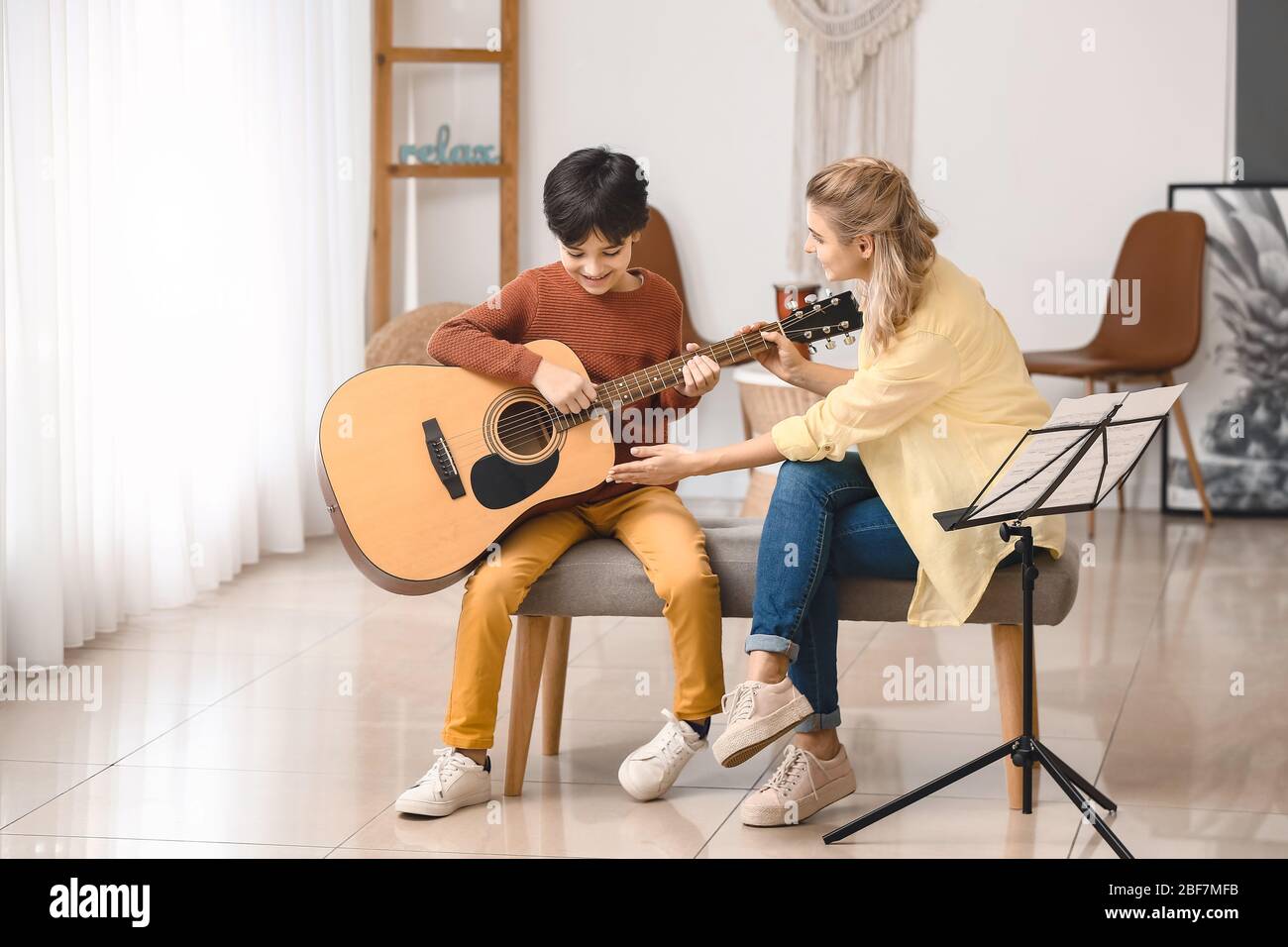 Private music teacher giving guitar lessons to little boy at home Stock ...