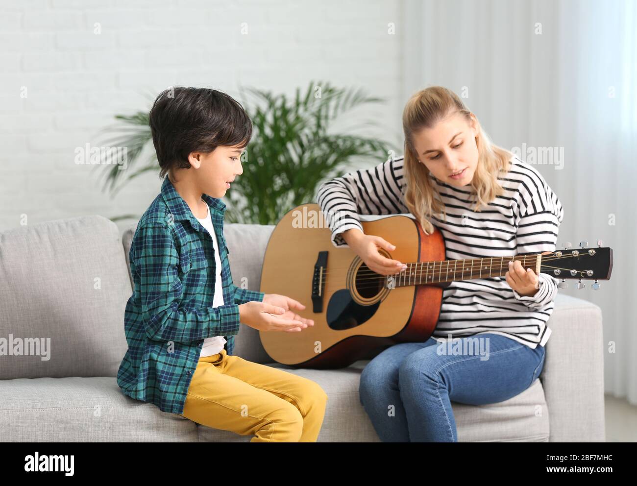 Private music teacher giving guitar lessons to little boy at home Stock ...