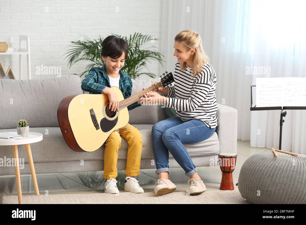 Private music teacher giving guitar lessons to little boy at home Stock ...