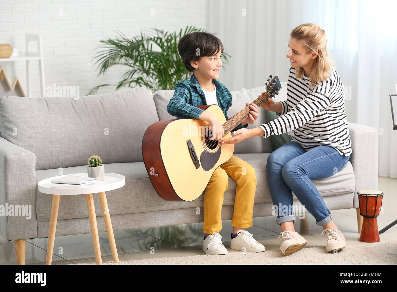 Private music teacher giving guitar lessons to little boy at home Stock ...