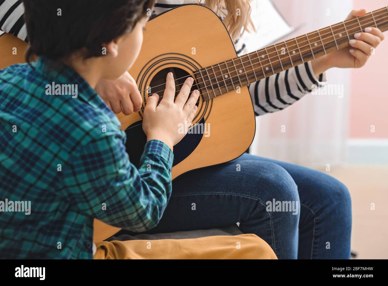 Private music teacher giving guitar lessons to little boy at home Stock ...
