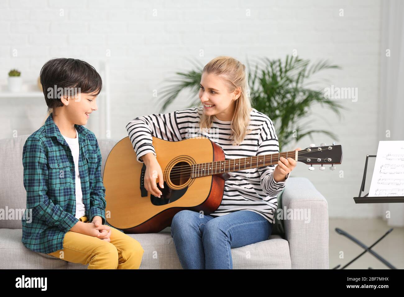 Private music teacher giving guitar lessons to little boy at home Stock ...