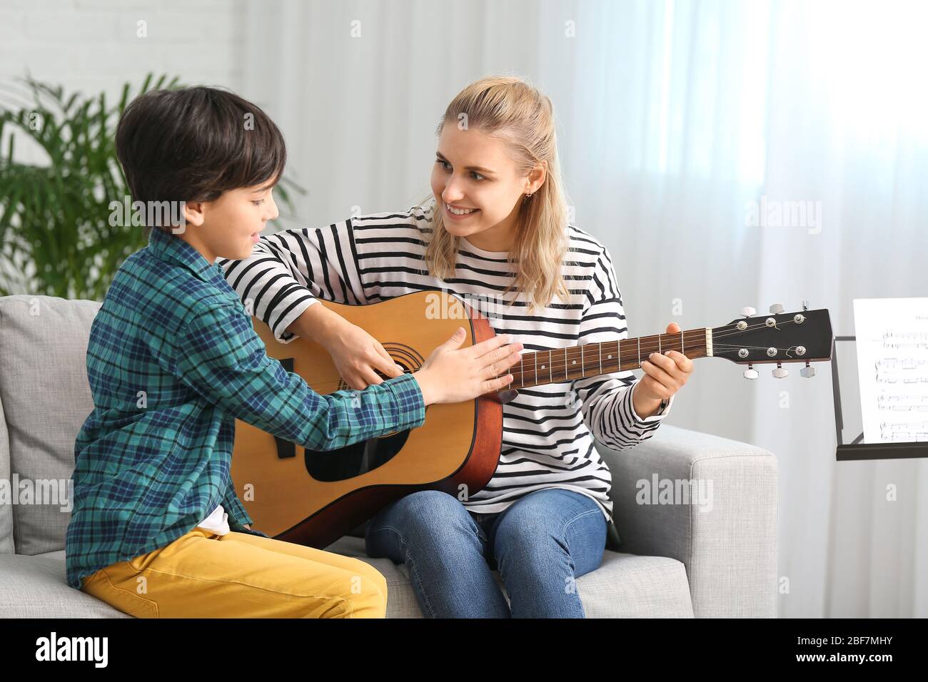 Private music teacher giving guitar lessons to little boy at home Stock ...