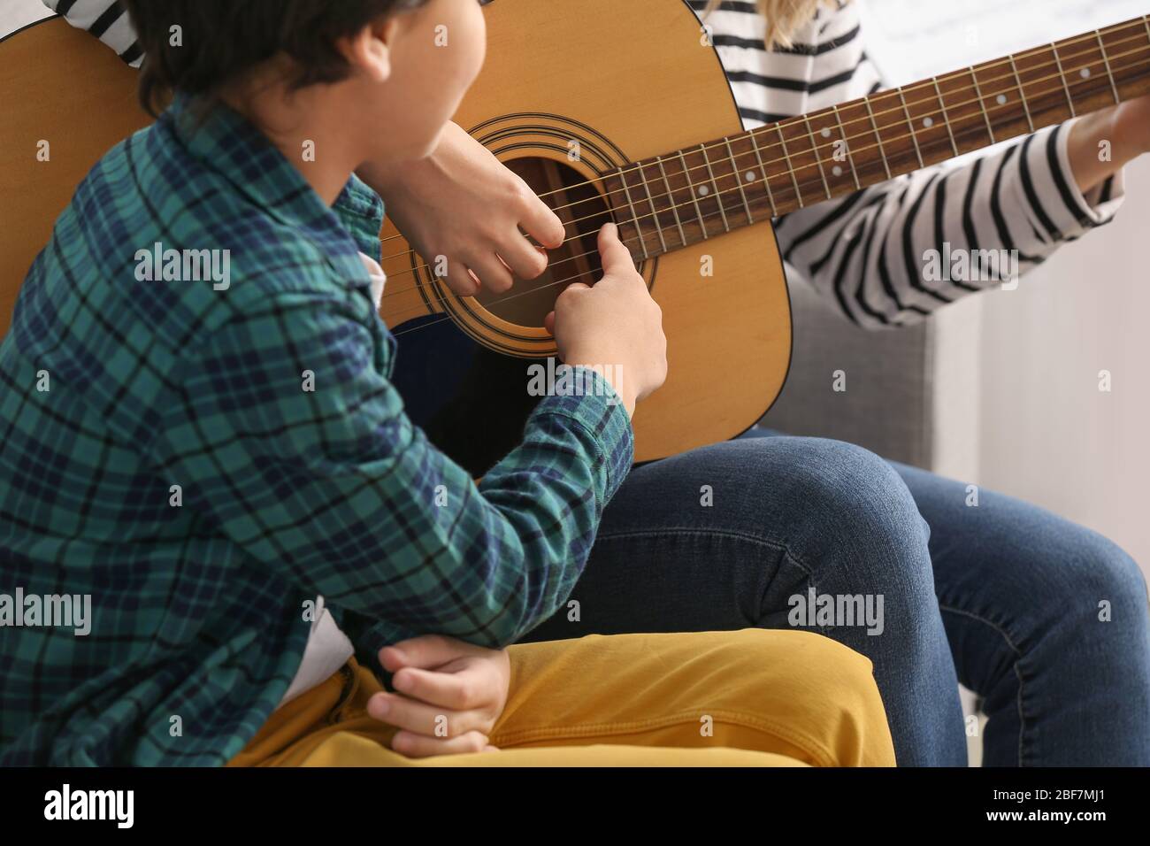 Private music teacher giving guitar lessons to little boy at home Stock ...