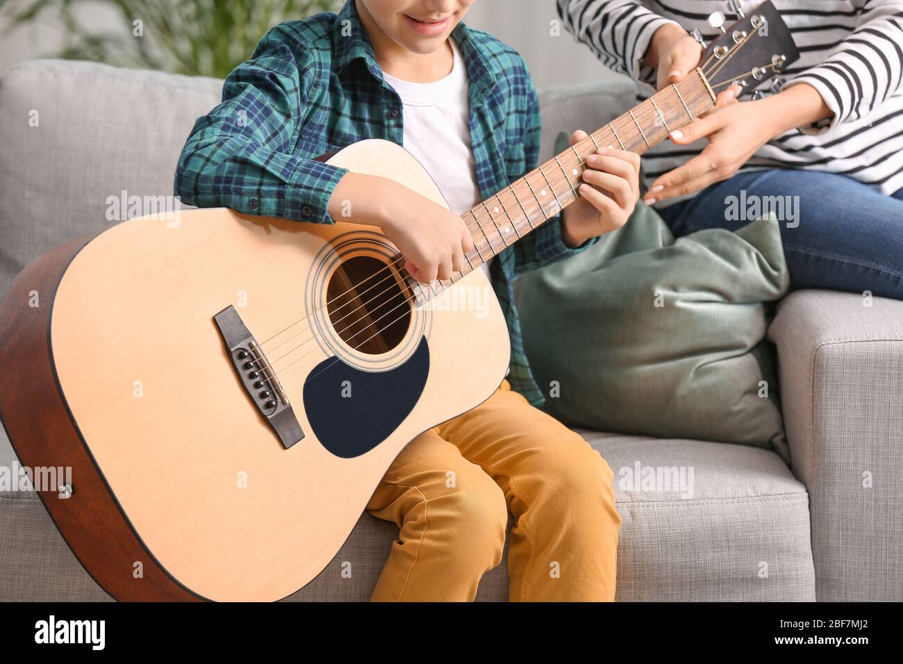 Private music teacher giving guitar lessons to little boy at home Stock ...