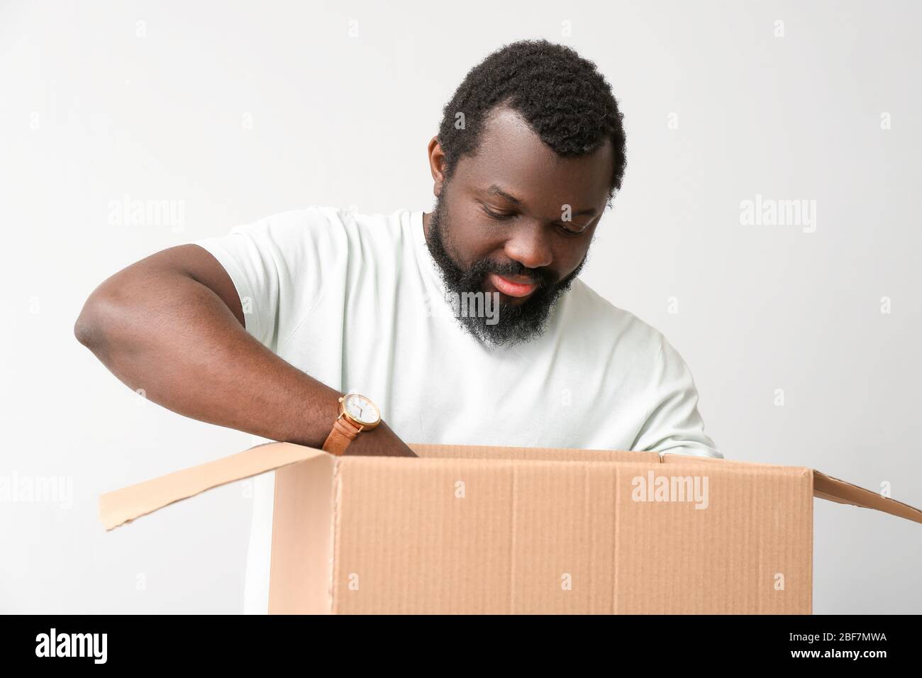 African-American man opening box on white background Stock Photo - Alamy