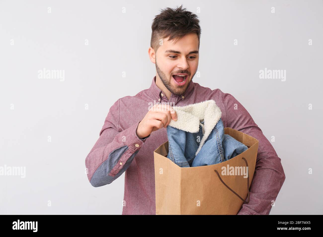 Young man with received new clothes on light background Stock Photo - Alamy