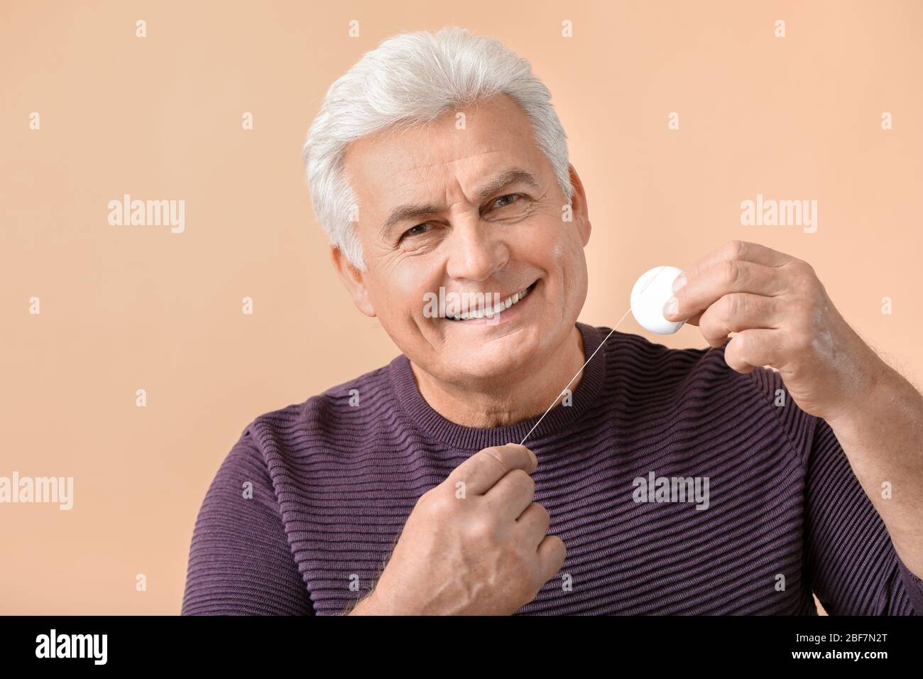 Senior man flossing teeth on color background Stock Photo - Alamy