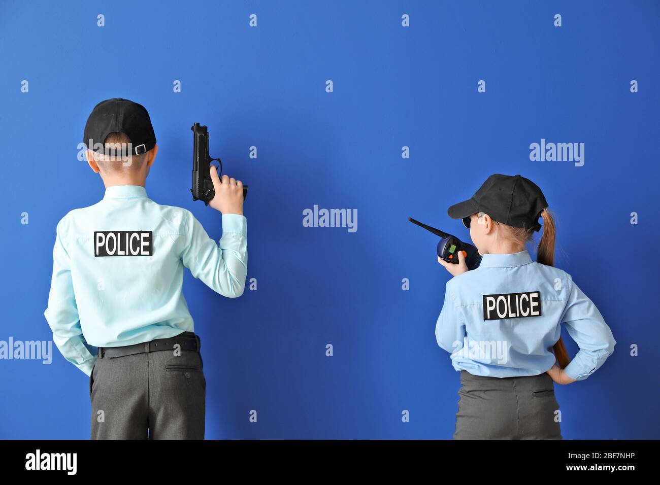 Cute little police officers on color background, back view Stock Photo ...