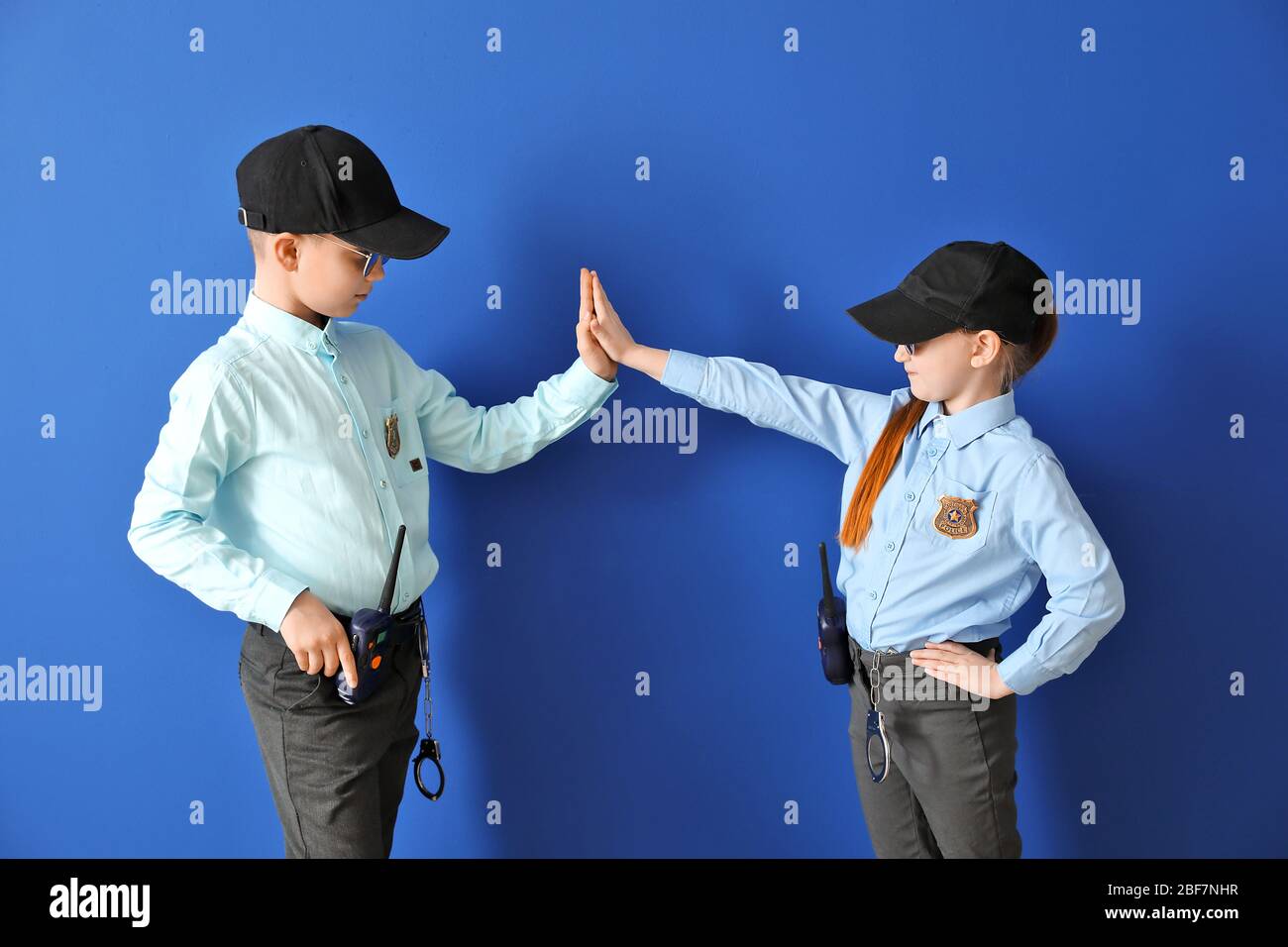 Cute little police officers giving each other high-five on color ...