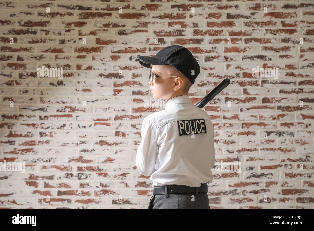 Cute little police officer on brick background Stock Photo - Alamy