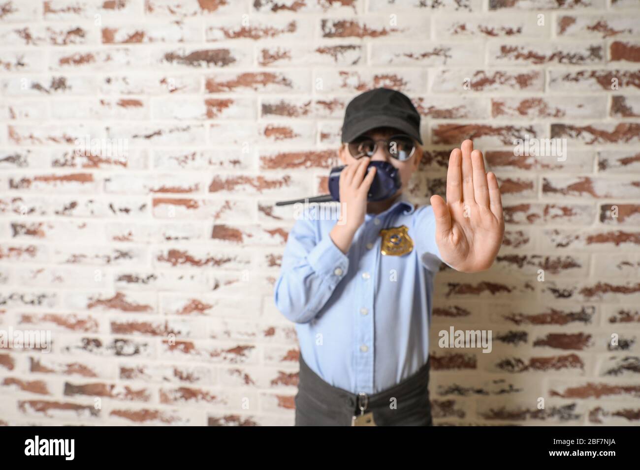 Cute little police officer on brick background Stock Photo - Alamy