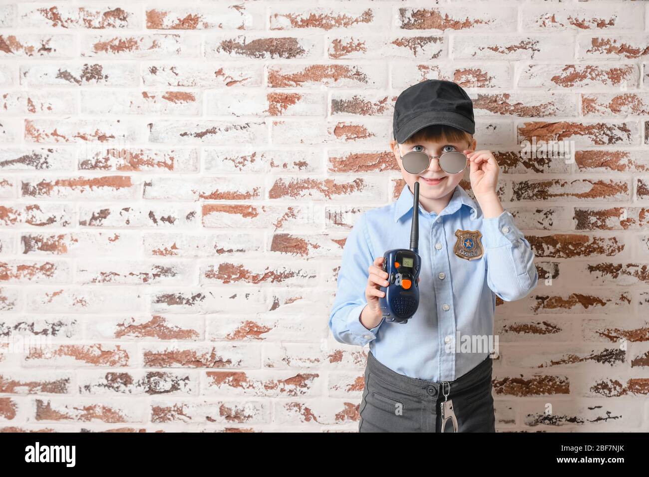 Cute little police officer on brick background Stock Photo - Alamy