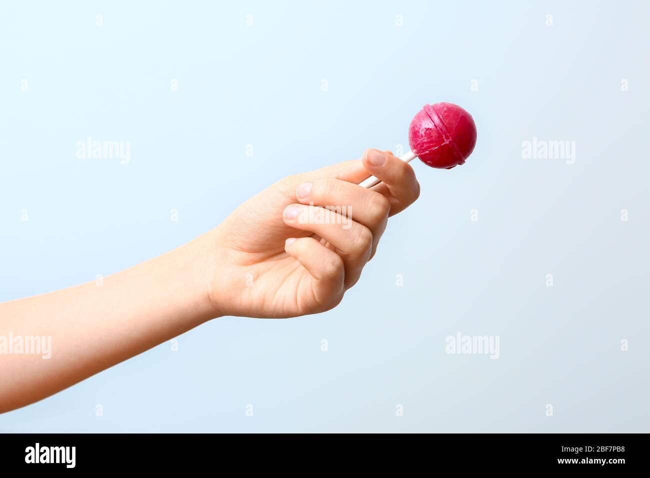 Female hand with sweet lollipop on light background Stock Photo - Alamy