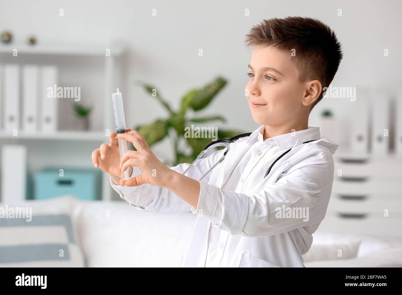 Cute little doctor with syringe in clinic Stock Photo - Alamy