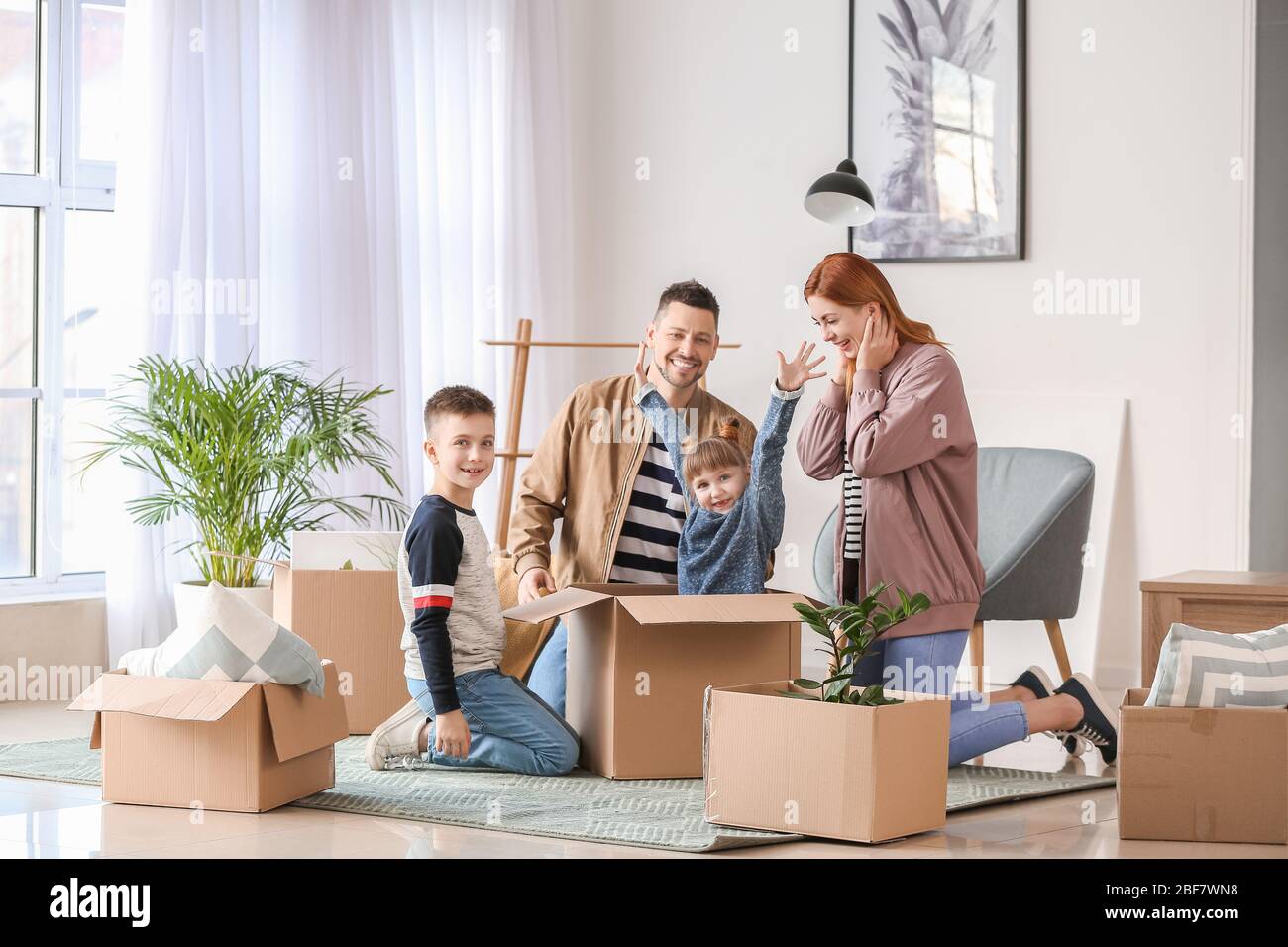 Family unpacking moving boxes in their new house Stock Photo - Alamy