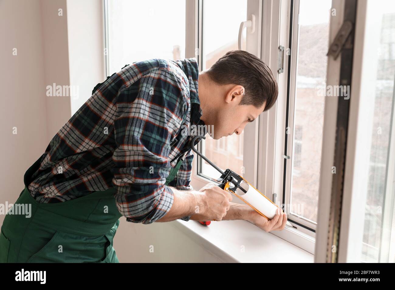 Male worker installing window in flat Stock Photo - Alamy