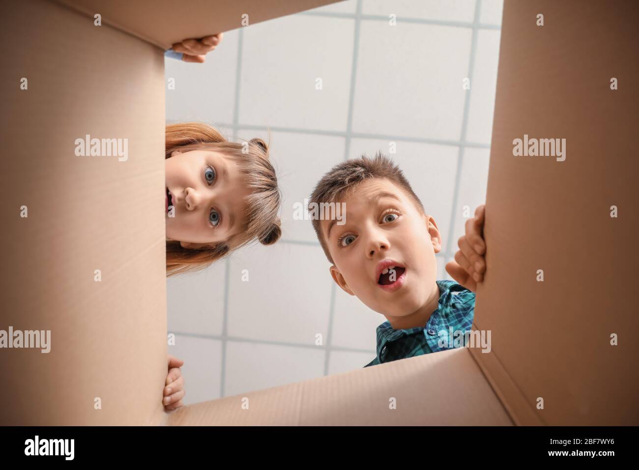 Curious children looking inside cardboard box, bottom view Stock Photo ...