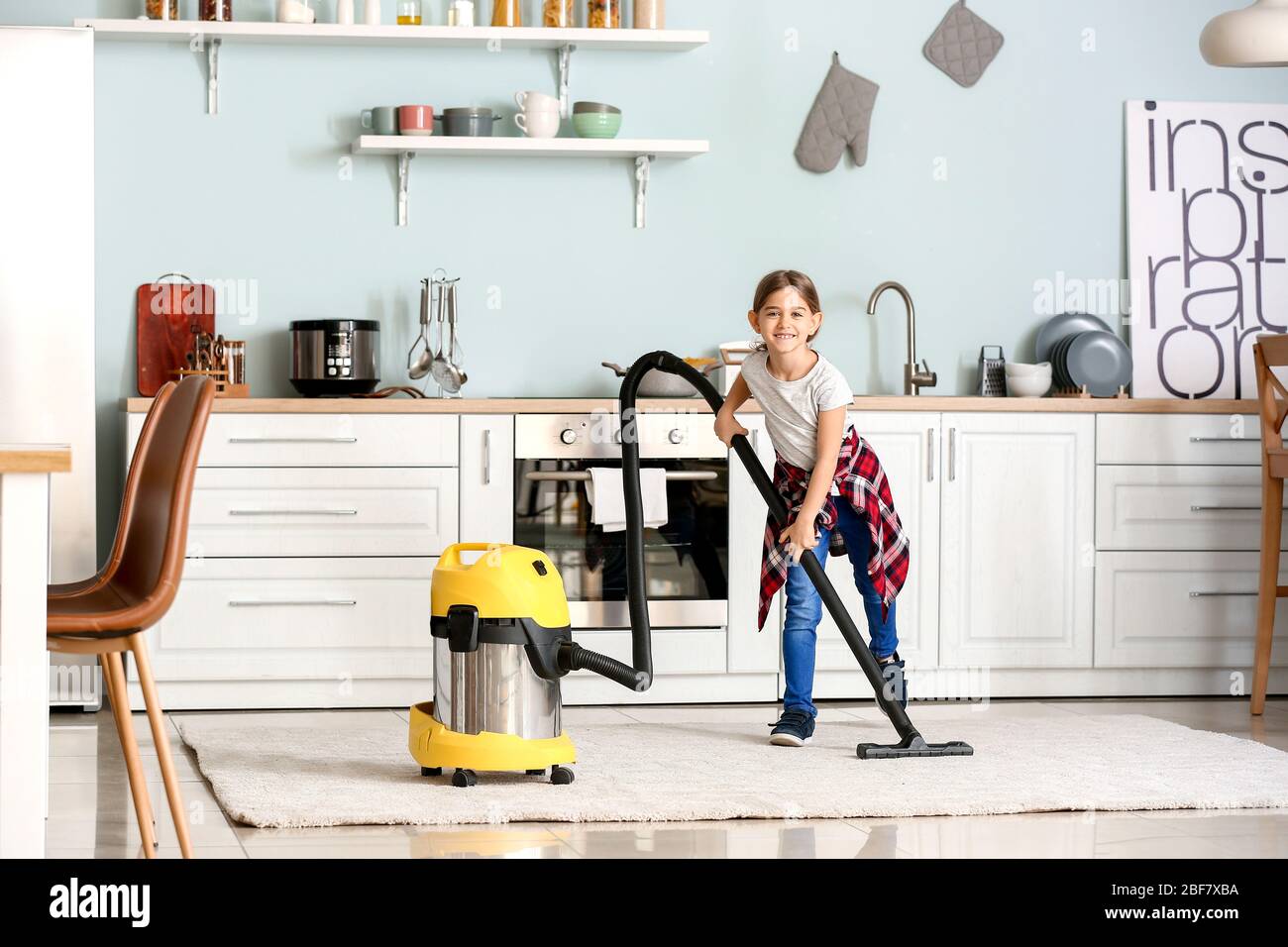 Little girl hoovering floor in kitchen Stock Photo - Alamy