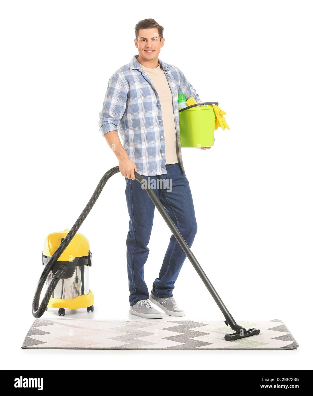 Young man hoovering carpet against white background Stock Photo - Alamy