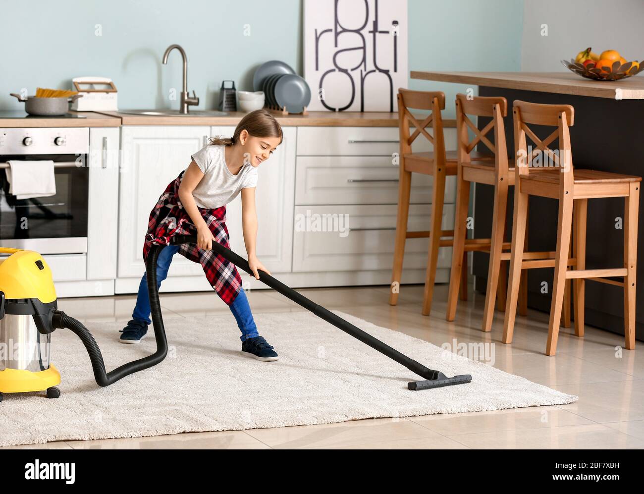 Little girl hoovering floor in kitchen Stock Photo - Alamy