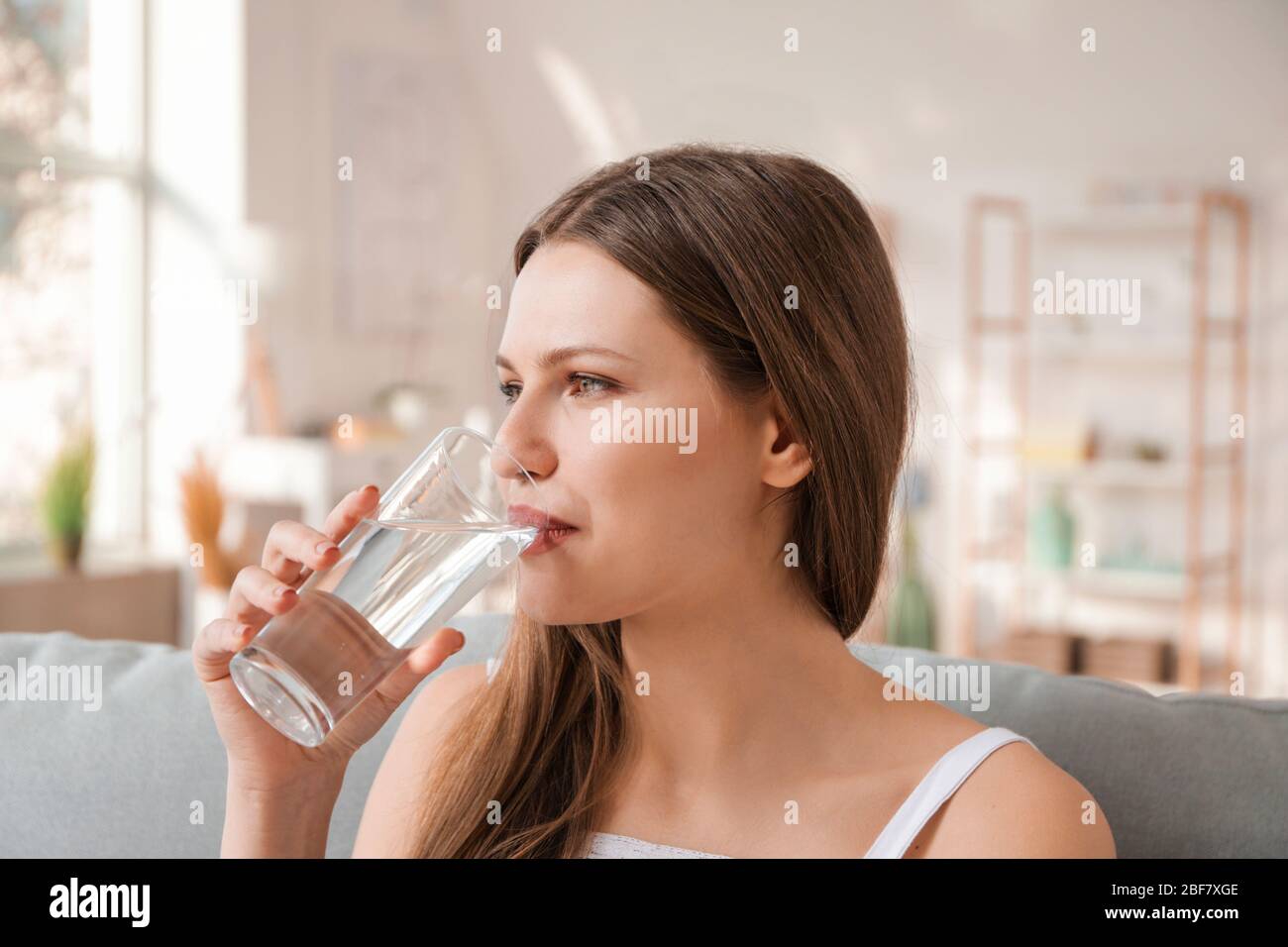 Beautiful young woman drinking water at home Stock Photo - Alamy