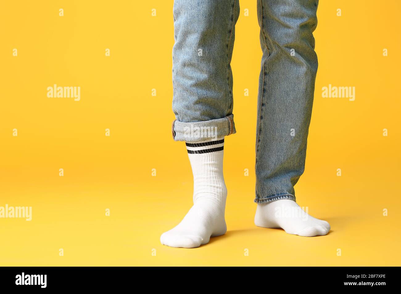 Male legs in socks and jeans on color background Stock Photo - Alamy