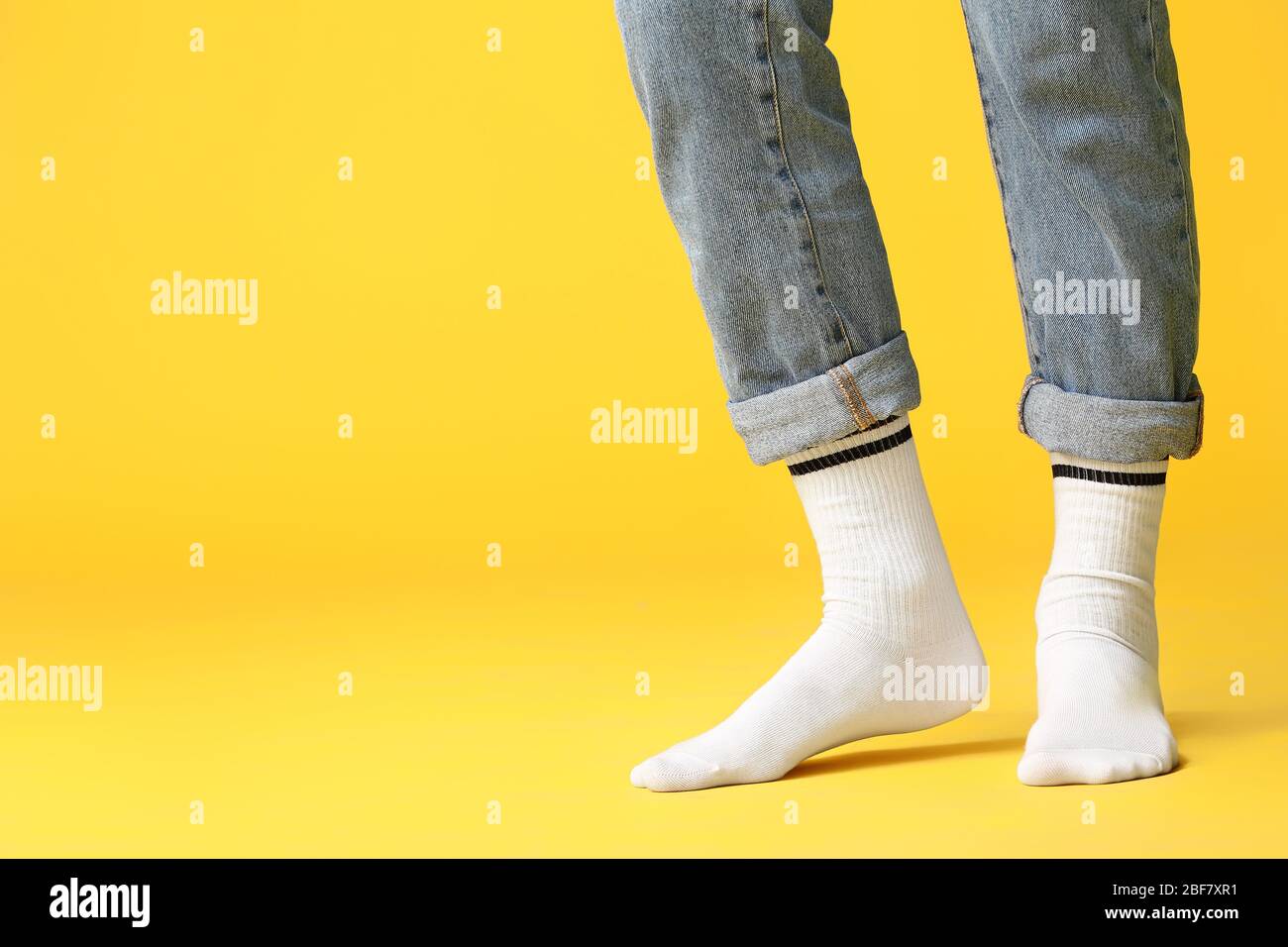 Male legs in socks and jeans on color background Stock Photo - Alamy