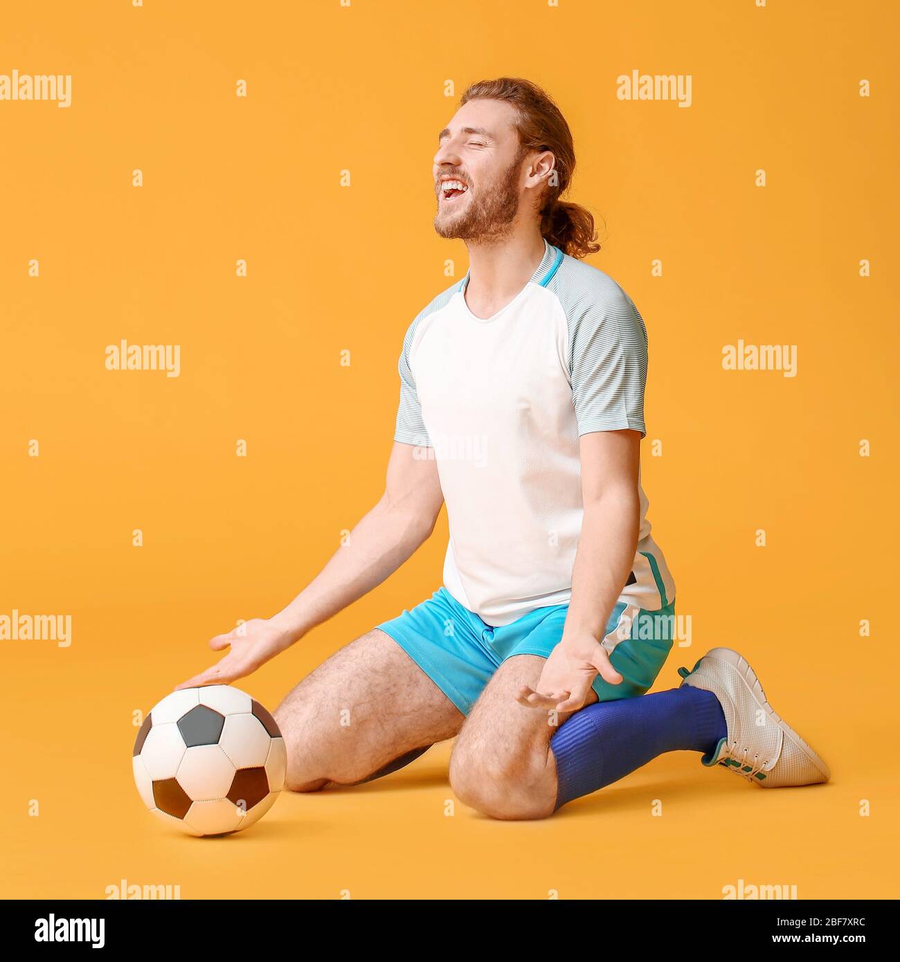 Happy football player on color background Stock Photo - Alamy